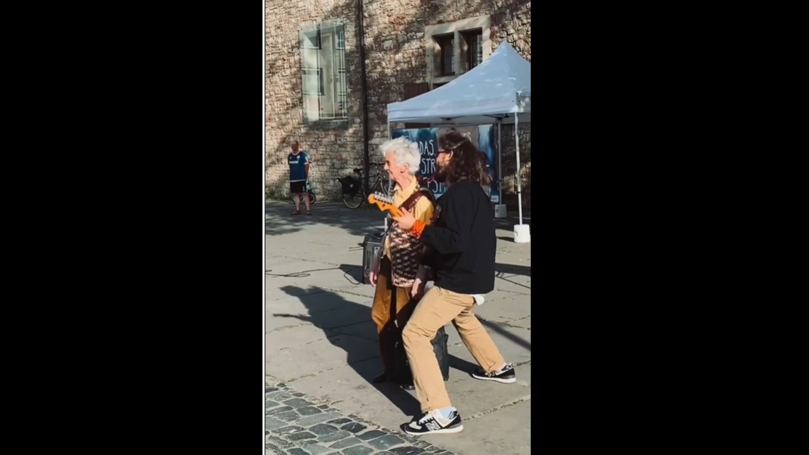 Elderly woman grooves on the street as man plays guitar. Watch ...